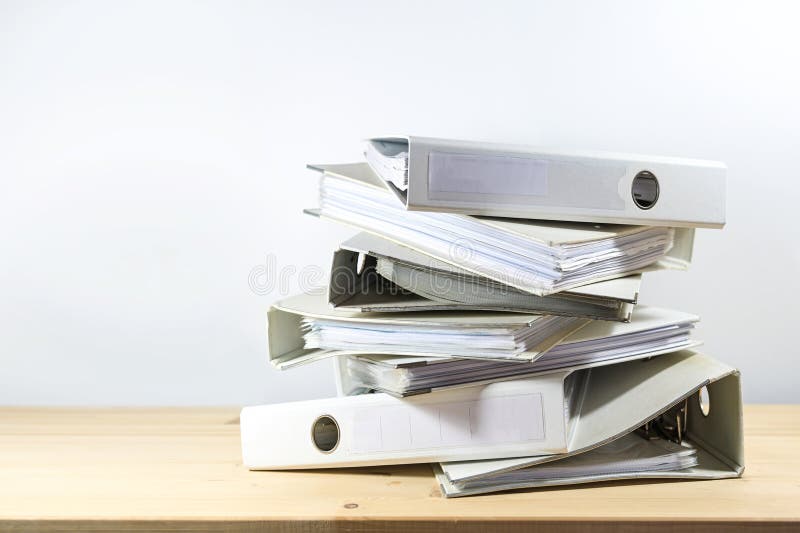 Stack of Ring Binders on a Wooden Office Desk Against a Light Gray Wall ...