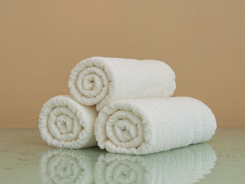 Stack of Rolled White Towels on a Reflective Surface for Spa or ...