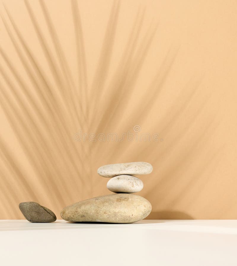 Stack of Round Stones and and the Shadow of a Palm Leaf on a Beige ...