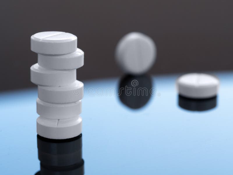 A Stack of Round Tablets and Two Pills Separately on a Mirror Surface ...