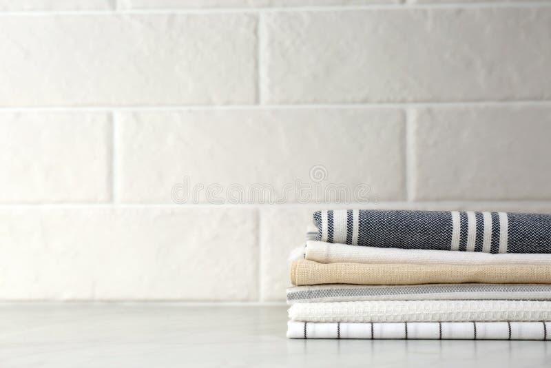 Stack of Soft Kitchen Towels on Table Near Brick Wall, Space for Text ...