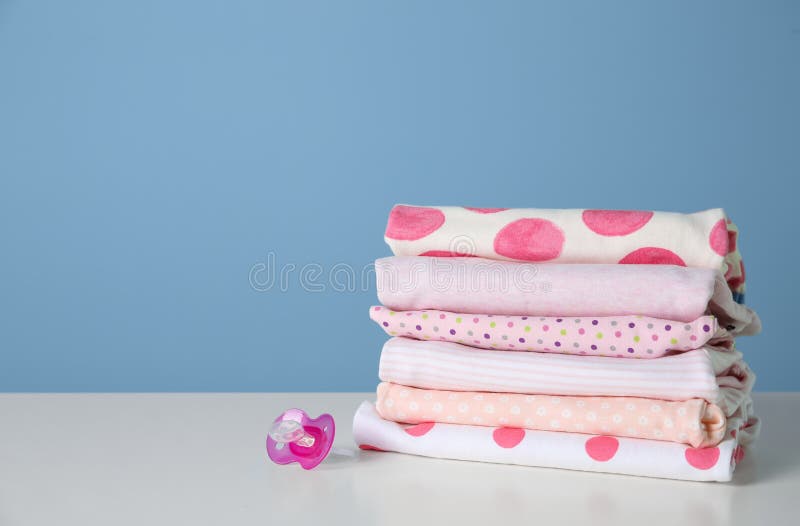 Stack of Stylish Child Clothes and Pacifier on Table Stock Image ...