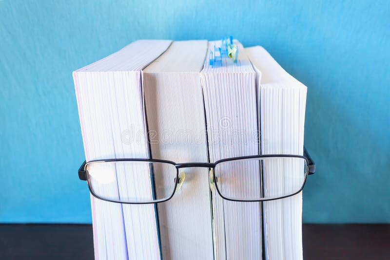 A Stack of Thick New Books and Black Glasses Depict a Person`s Face ...