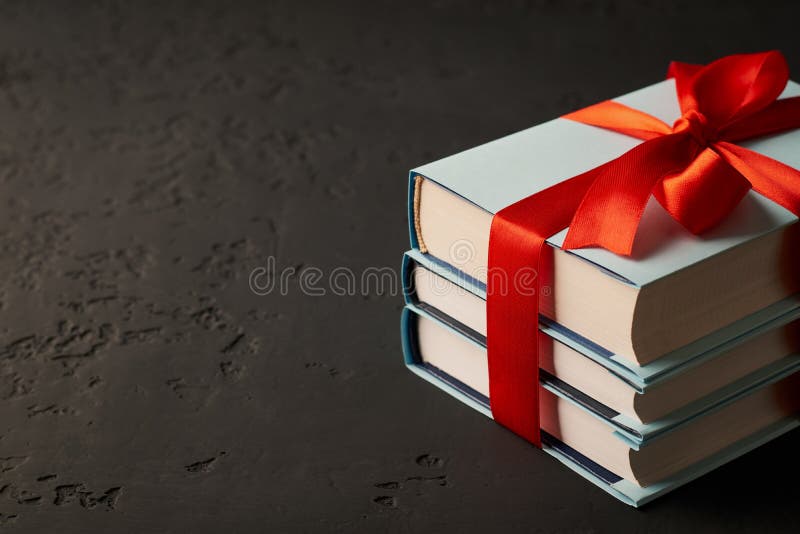 A Stack of Three Books Tied with a Red Ribbon with a Bow on a Dark ...