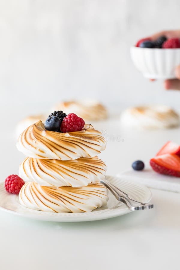 A Stack of Toasted Meringues and Berries with a Hand Holding a Small ...