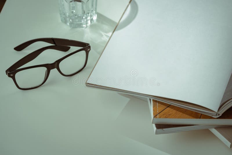 Stack of White Paperbacks and Glass of Water on White Table Stock Image ...
