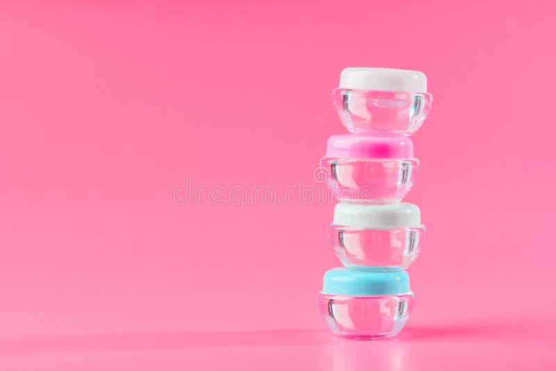 Stacked Clear Plastic Containers with Colored Lids on Pink Background ...