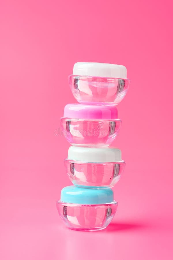 Stacked Clear Plastic Containers with Colored Lids on Pink Background ...
