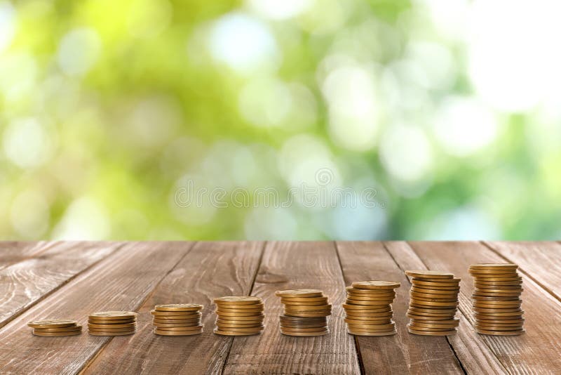 Stacked Coins on Wooden Table Against Blurred Background. Investment ... Stacked Coins on Wooden Table Against Blurred Background. Investment ...