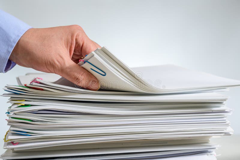 A Stacked Document or Report and the Hand of a Businessman Holding it ...