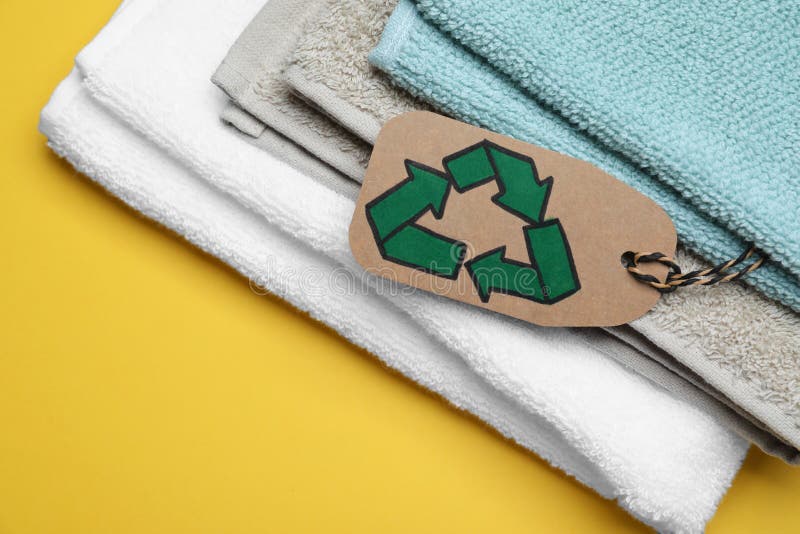 Stacked Towels with Recycling Label on Yellow Background, Closeup Stock ...