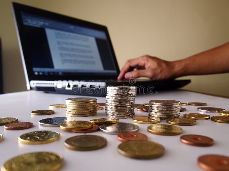 Stacks of Coins and a Hand Working on a Laptop Computer Stock Photo ...