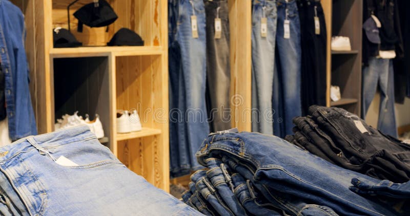 Stacks of Folded Jeans Sit on a Wooden Display Table, with Shirts and ...