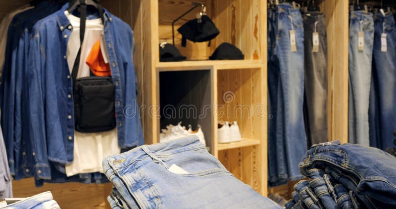 Stacks of Folded Jeans Sit on a Wooden Display Table, with Shirts and ...