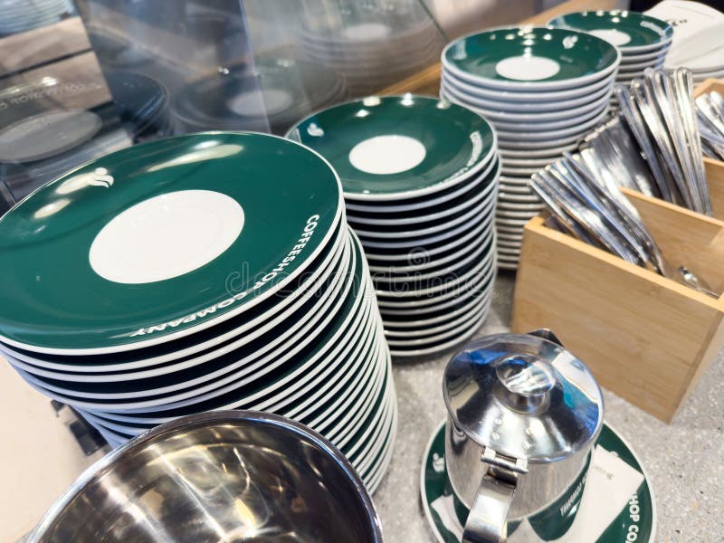 Stacks of Plates with Green Trim and Stainless Steel Utensils in a ...