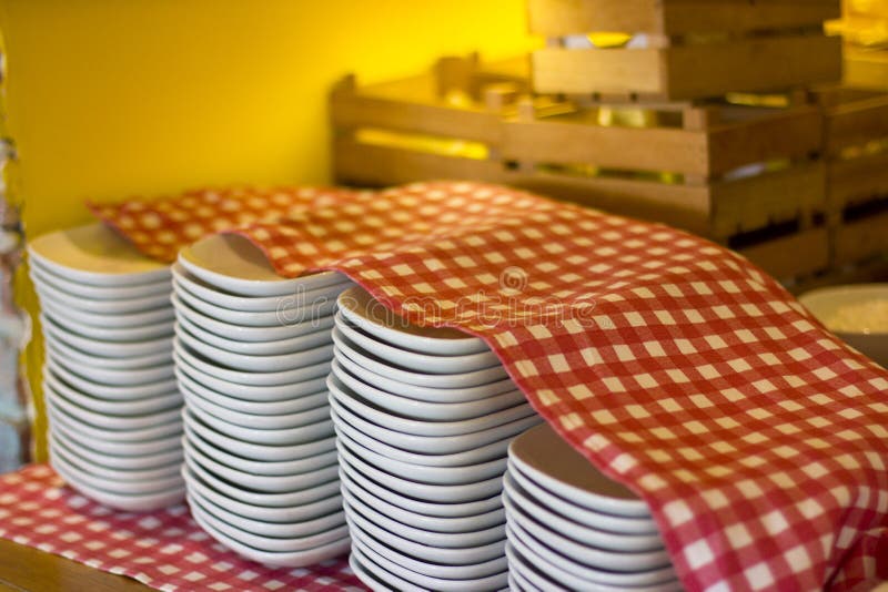 Stacks of White Plates Under a Checkered Red and White Tablecloth in a ...