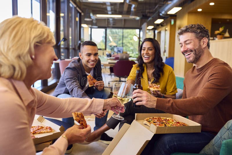 Staff at Informal Meeting in Office with Takeaway Pizza and Drinks ...