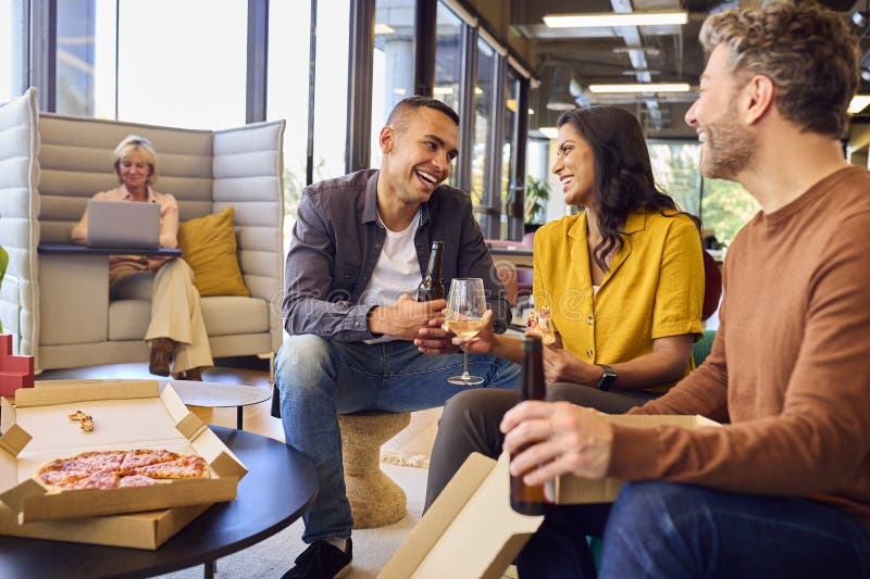 Staff at Informal Meeting in Office with Takeaway Pizza and Drinks ...