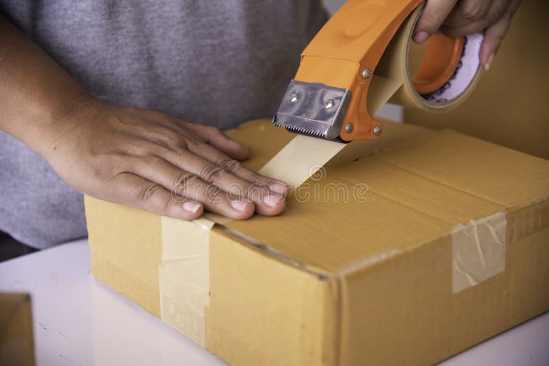 The Staff is Using the Tape To Pack the Package Goods To the Customer ...