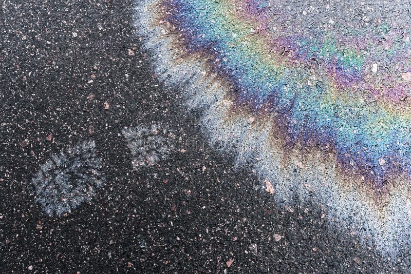 A Stain of Multi-colored Gasoline Spill on the Wet Sidewalk and a Trace ...