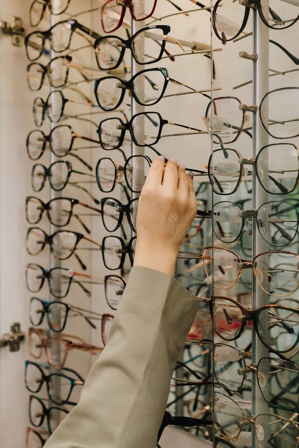 Stand of Eyeglasses with Different Frames in the Optical Store. Customer Chooses Eyeglasses with ...