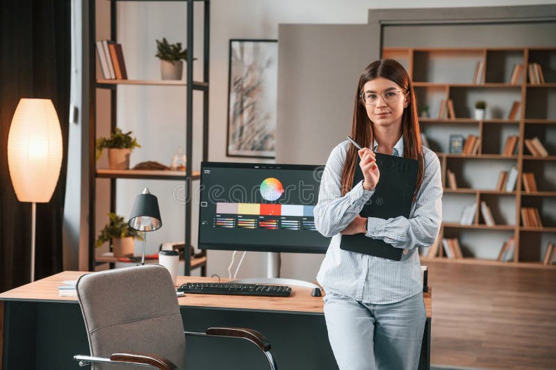 Standing Against Pc and Holding Notepad. Young Female Designer is in ...