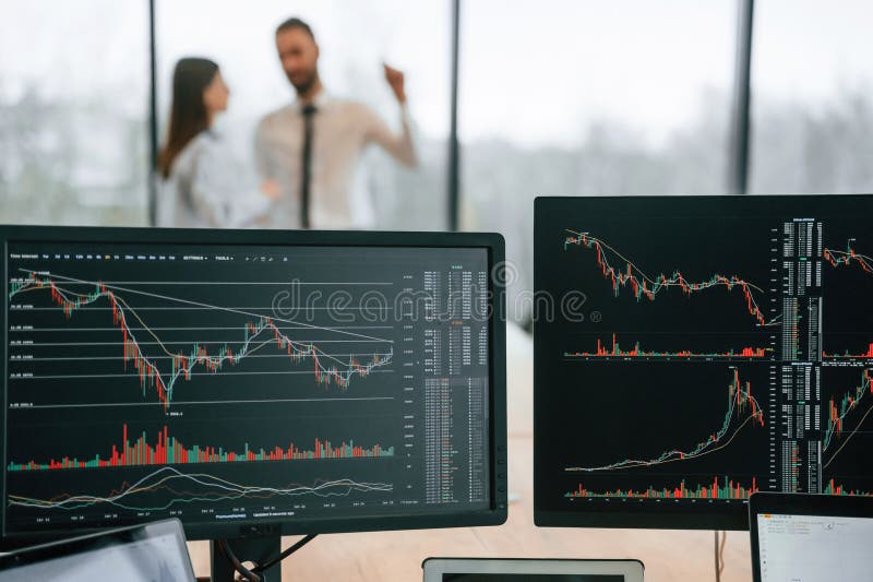 Standing Behind the Monitors with Graphs on Them. Two Employees are ...