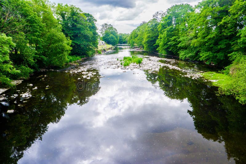 Standing on a Bridge Looking Down a Slow Moving River with Green Banks ...