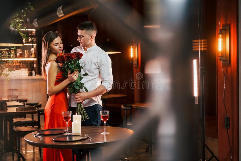 Standing with Flowers. Romantic Couple Have Dinner in the Restaurant ...