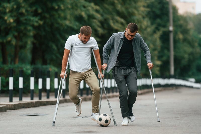 Standing, Having Fun, Playing Soccer. Two Men with Crutches is Outdoors ...
