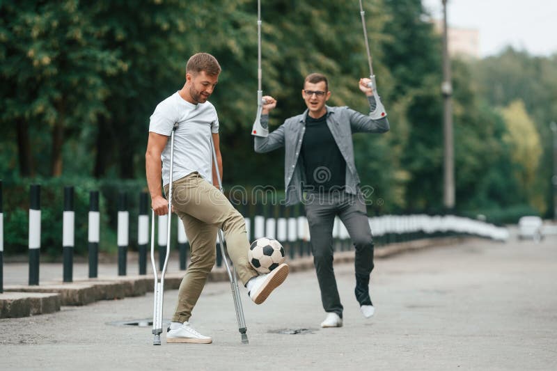 Standing, Having Fun, Playing Soccer. Two Men with Crutches is Outdoors ...