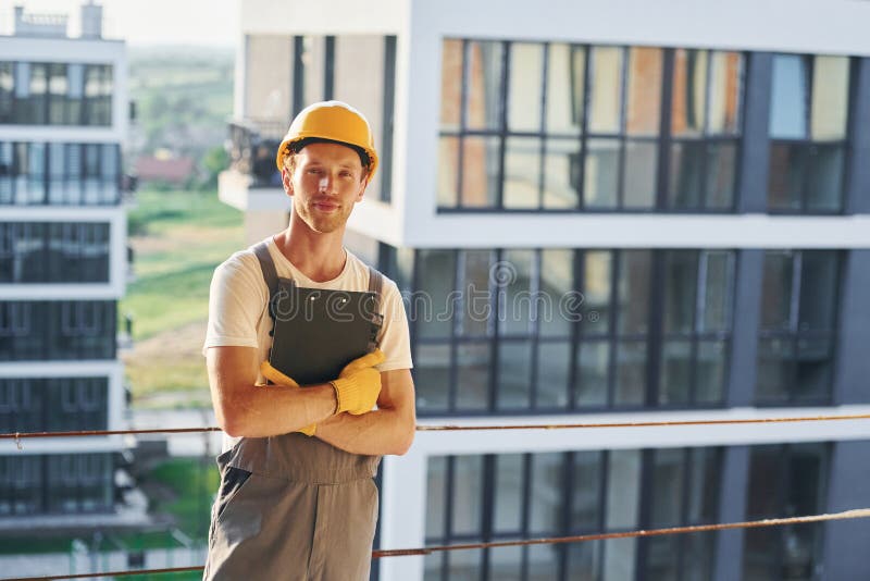 Standing High Up. Young Man Working in Uniform at Construction at ...