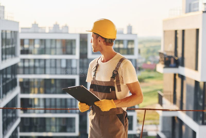 Standing High Up. Young Man Working in Uniform at Construction at ...