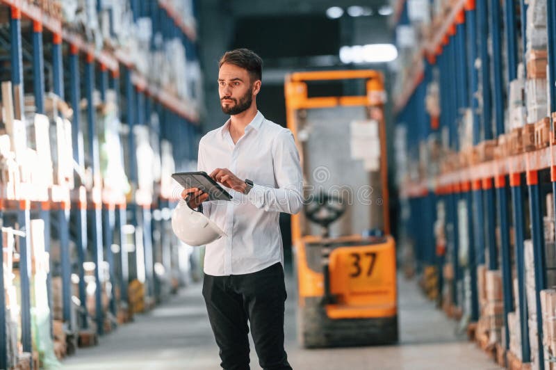 Standing and Holding Tablet in Hands. Storage Worker is in the ...