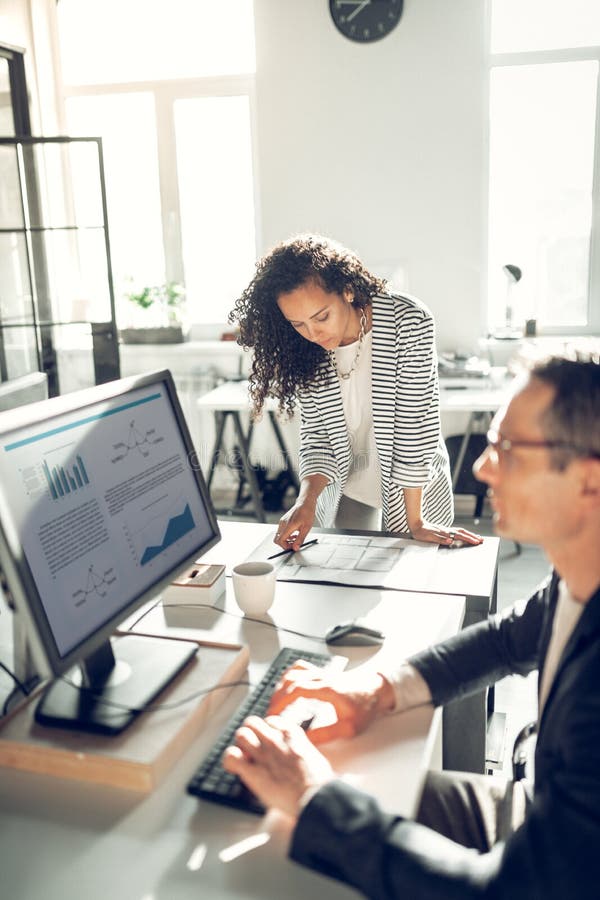 Curly Secretary Standing Near Her Boss Working on Computer Stock Photo ...