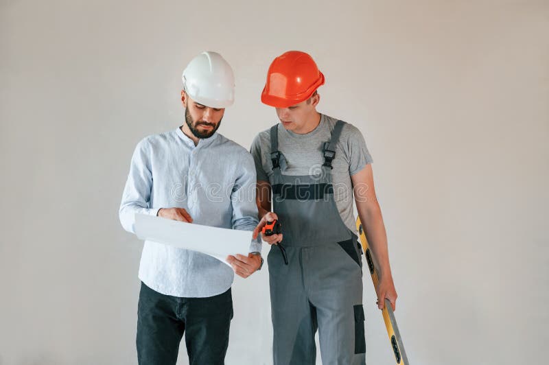 Standing and Reading the Plan. Two Men is Making Repairs in the ...