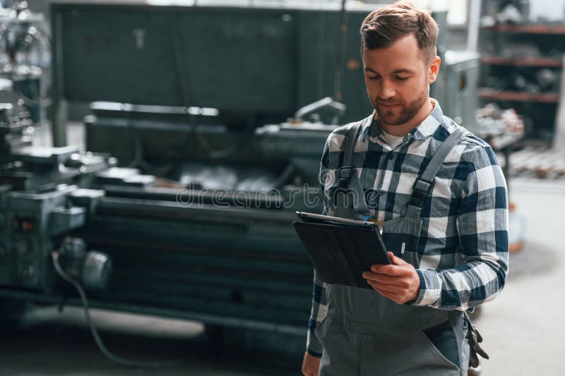 Standing and Using Graphic Tablet. Factory Male Worker in Uniform is ...