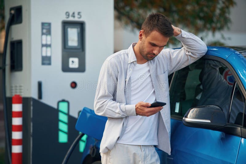 Standing and Waiting for Process Finished. Man with Blue Electric Car ...