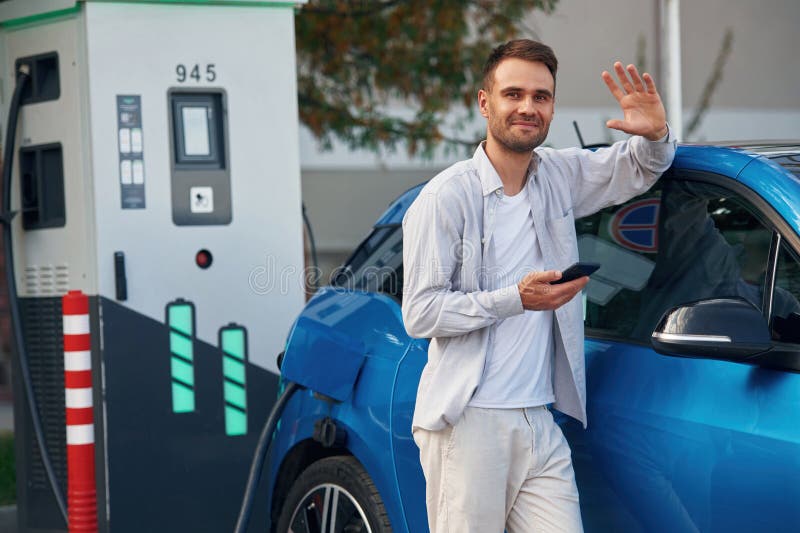 Standing and Waiting for Process Finished. Man with Blue Electric Car ...