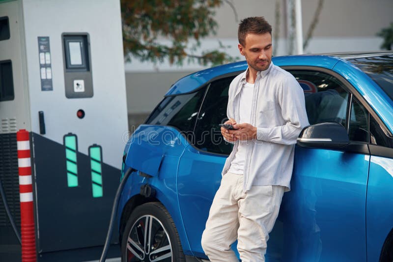 Standing and Waiting for Process Finished. Man with Blue Electric Car ...