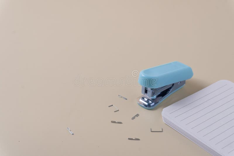 A Stapler with Scattered Staples beside a Neat Stack of Paper Ready To ...