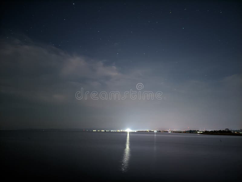 Starry Night Sky on the Edge of Town with the Reflection of Lights in ...