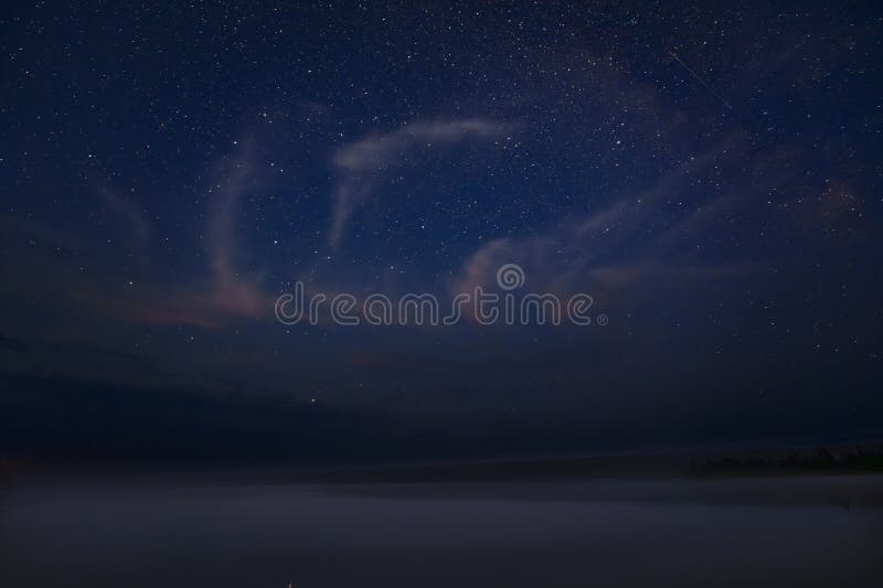 Starry Night Sky with Wispy Clouds Over a Tranquil Lake Stock Image ...