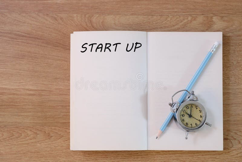 Start Up Concept on Notebook with Pencil and Clock on Wooden Table ...