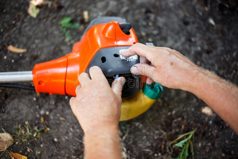 Starting a Gas Trimmer To Mow the Grass. a Man Opens the Choke To Make ...