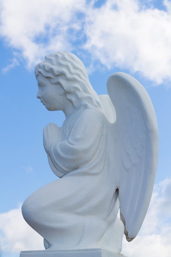 Statua Di Un Angelo Che Prega Su Uno Sfondo Di Fiori Sfocati Immagine ...