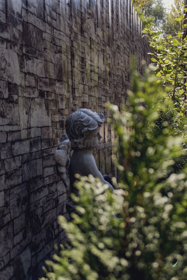 Statue on the Background of a Brick Wall among the Trees Stock Photo ...