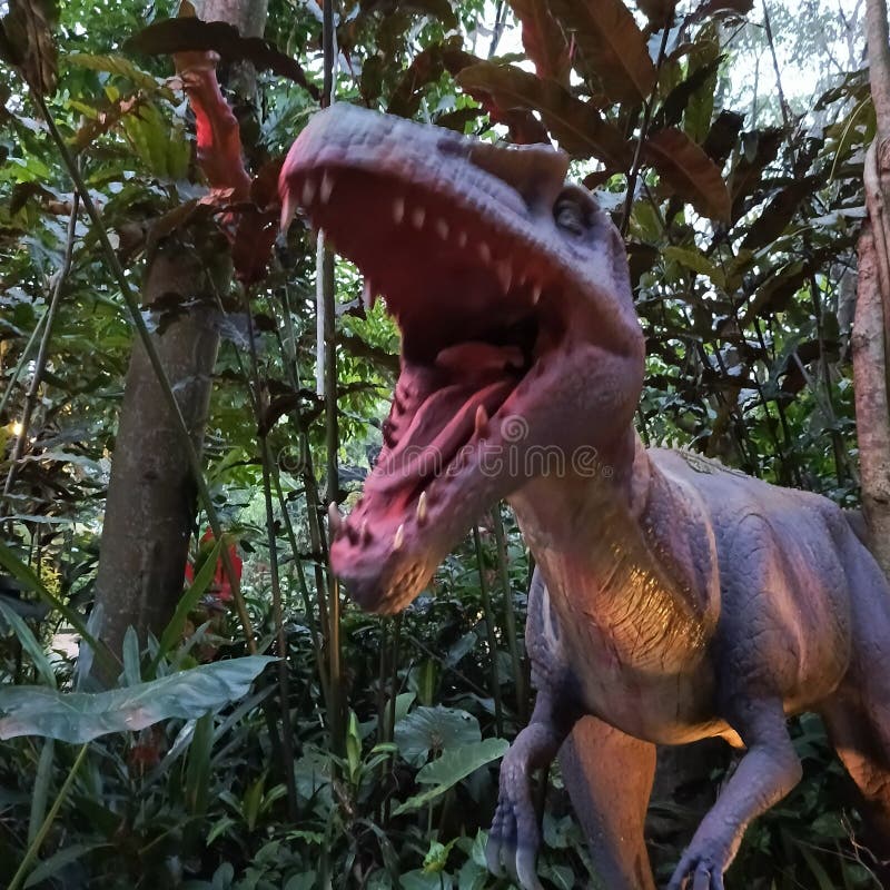 A Statue of a Dinosaur Roaring with Leaves in the Background Stock ...