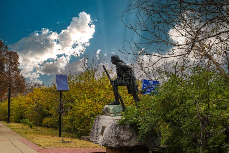 A Statue of an Explorer on the Sidewalk Surrounded by Lush Green and ...