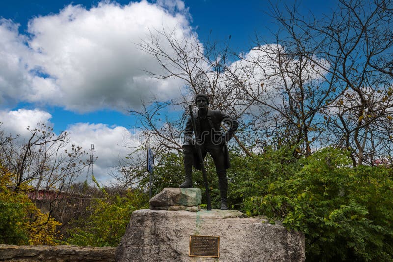 A Statue of an Explorer on the Sidewalk Surrounded by Lush Green and ...